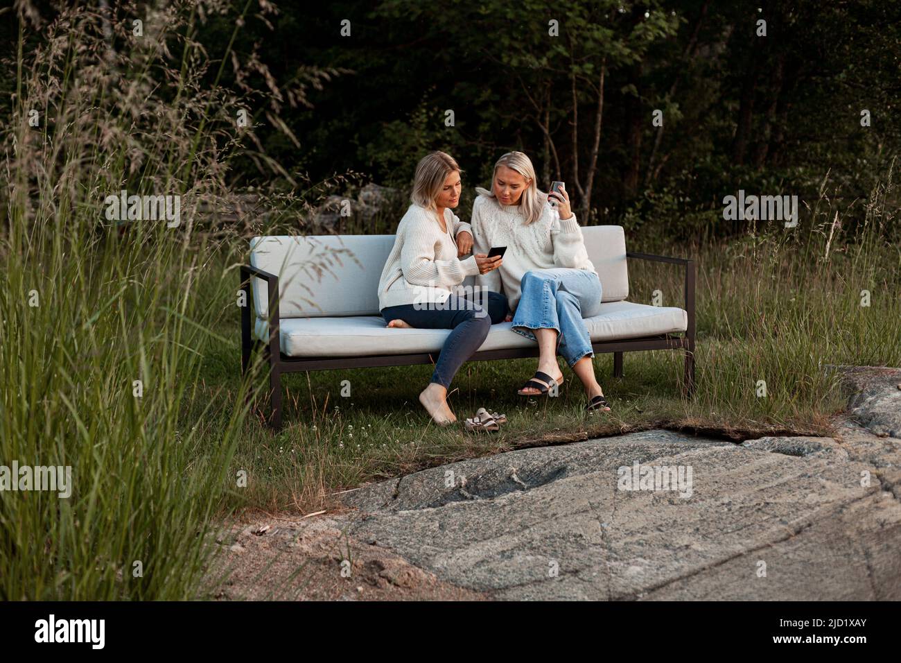 Female friends sitting on bench Stock Photo - Alamy