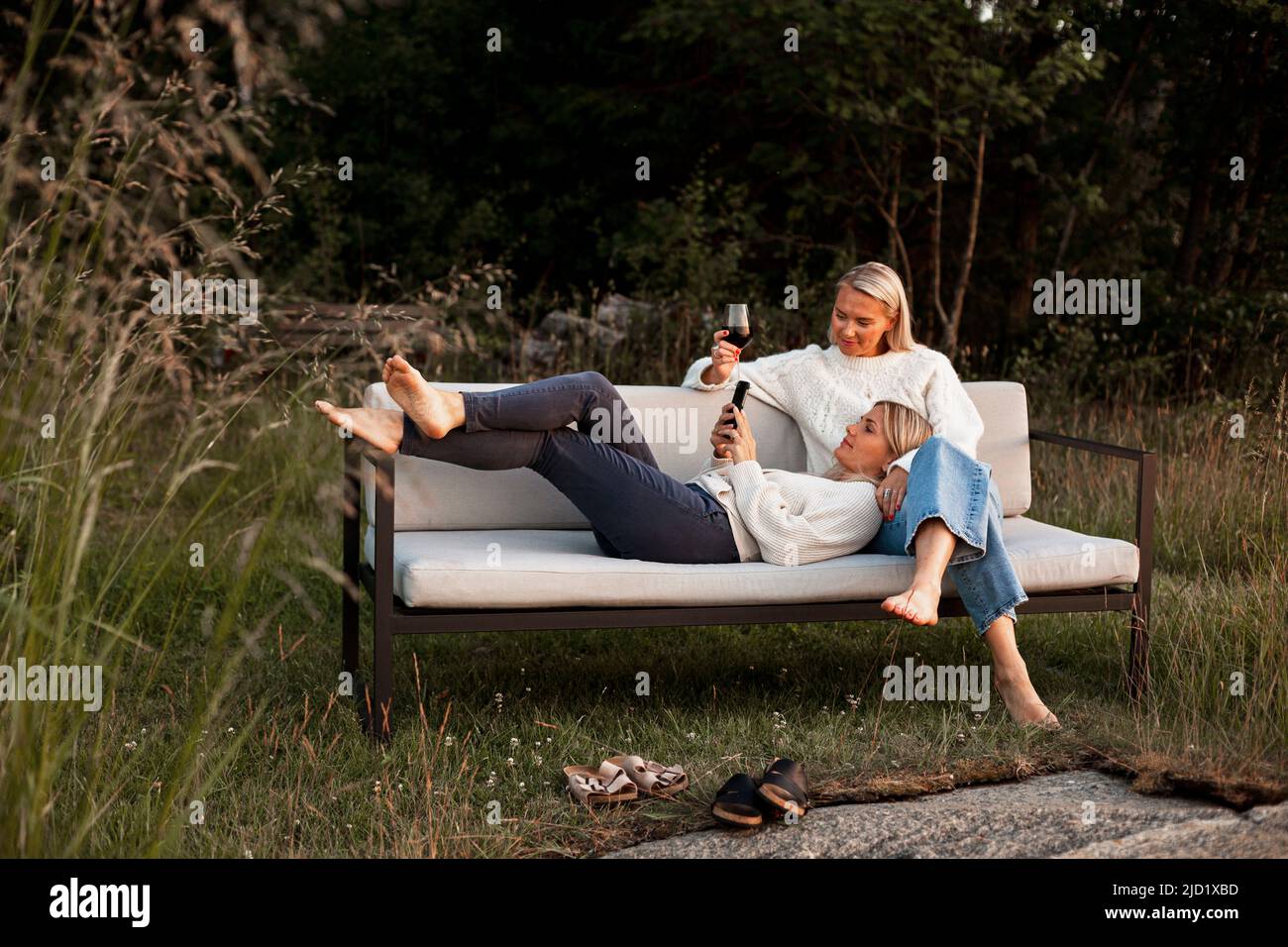 Female friends sitting on bench Stock Photo - Alamy