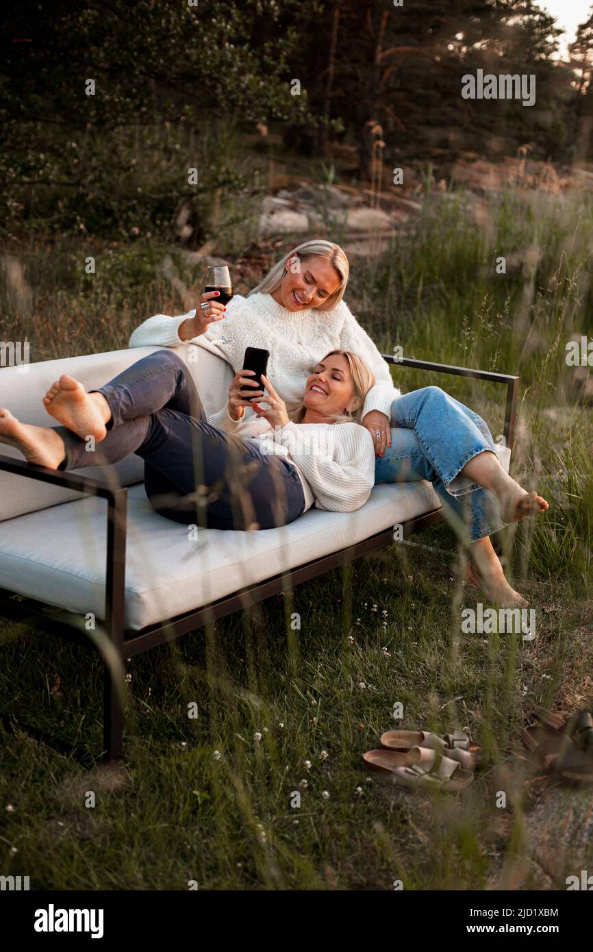 Female friends sitting on bench Stock Photo - Alamy