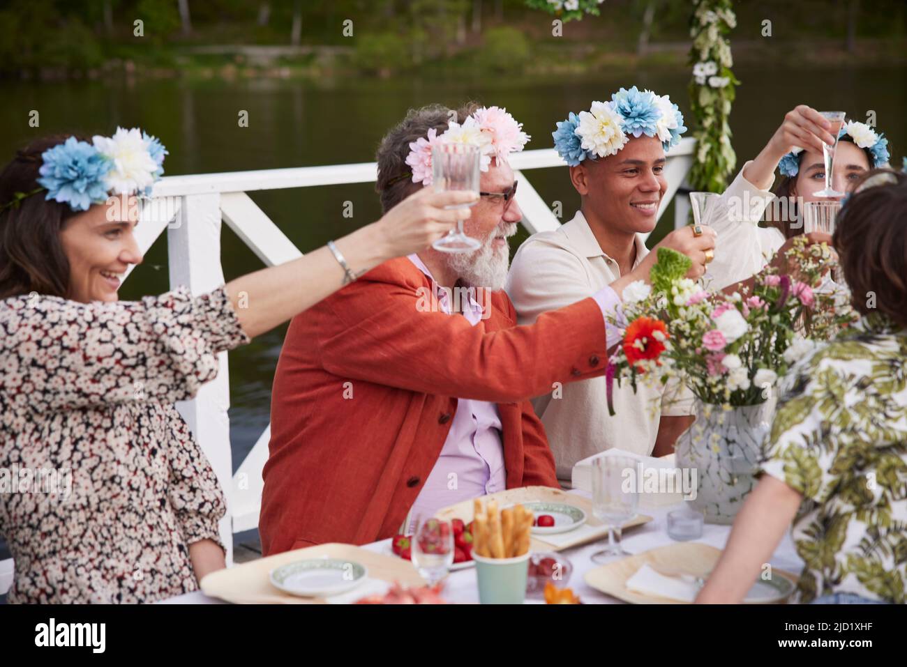 Family raising toast during midsummer dinner by lake Stock Photo - Alamy