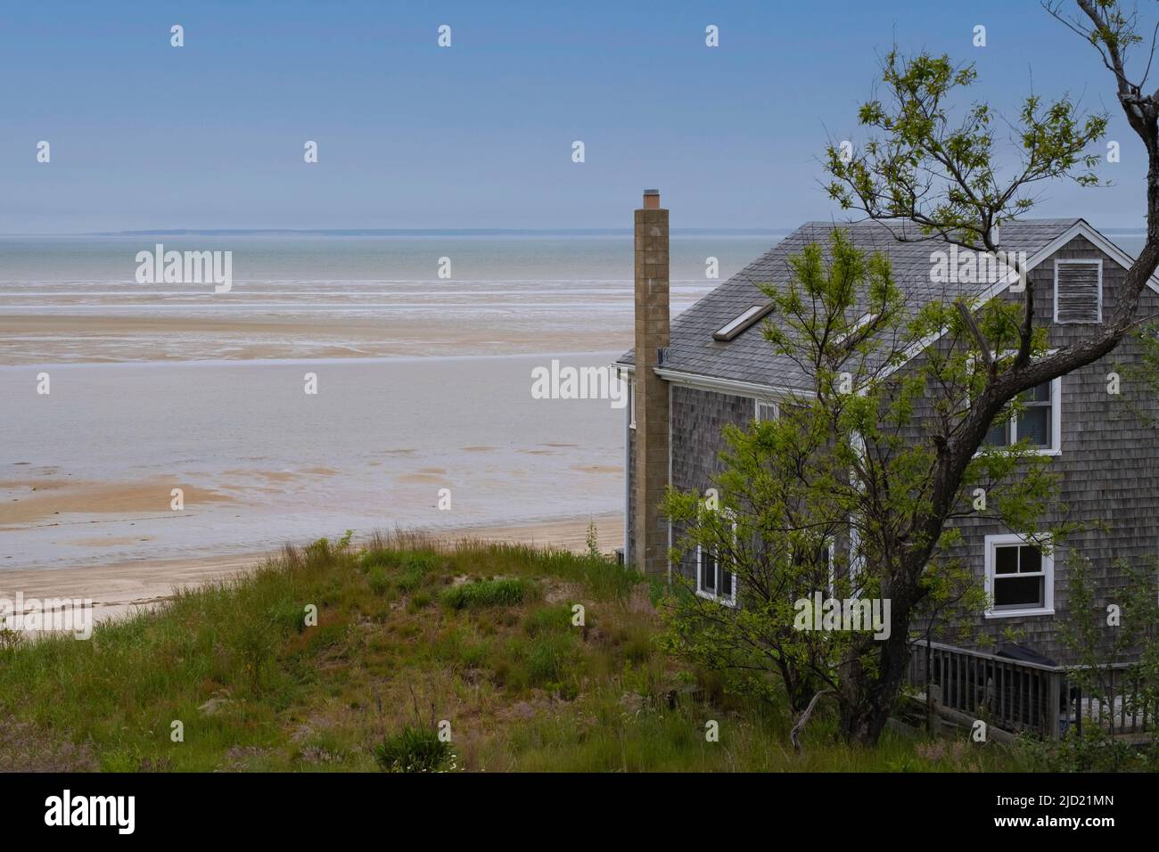View of Cape Cod beach at low tide with beach house and sand dune with ...