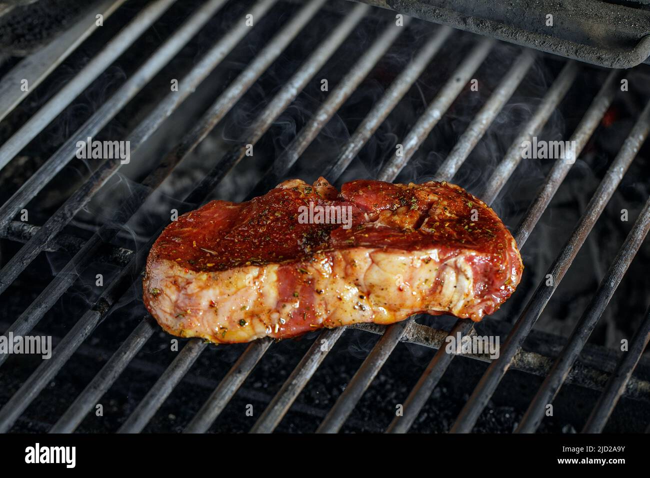 Raw meat beef steak grilling on rack charcoal stove with smoke on black ...