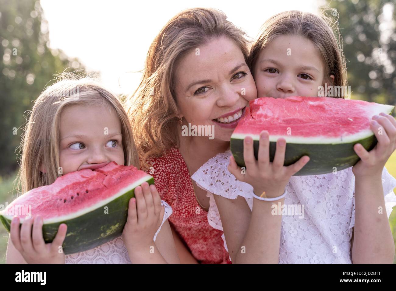 portrait of mom with cute daughters have fun while eating a slice of ...