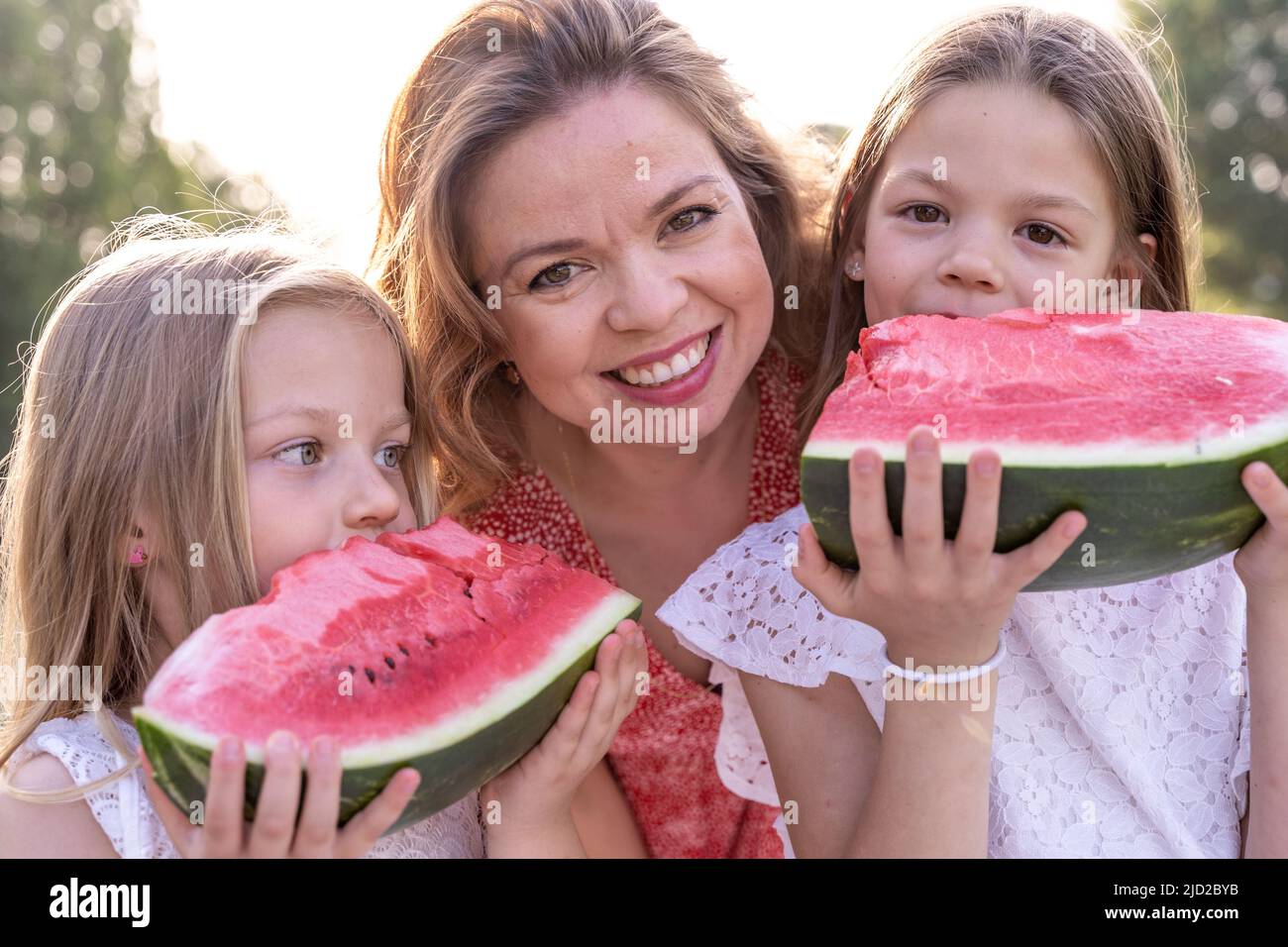 portrait of mom with cute daughters have fun while eating a slice of ...
