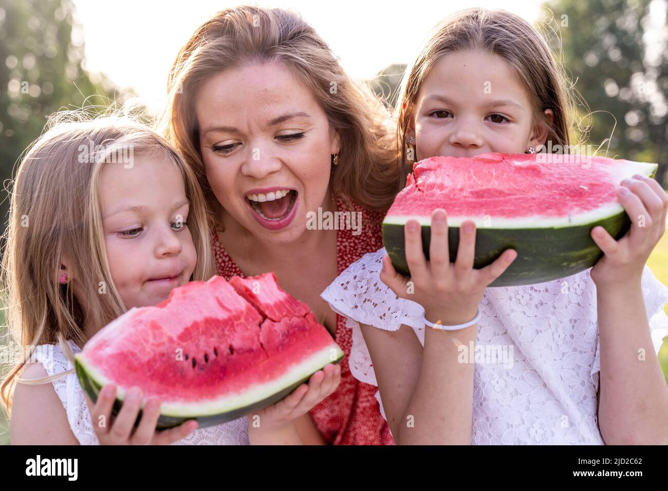 portrait of mom with cute daughters have fun while eating a slice of ...