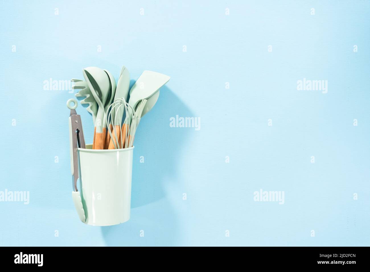 Flat lay. New blue silicone kitchen utensils with wooden handles on a ...