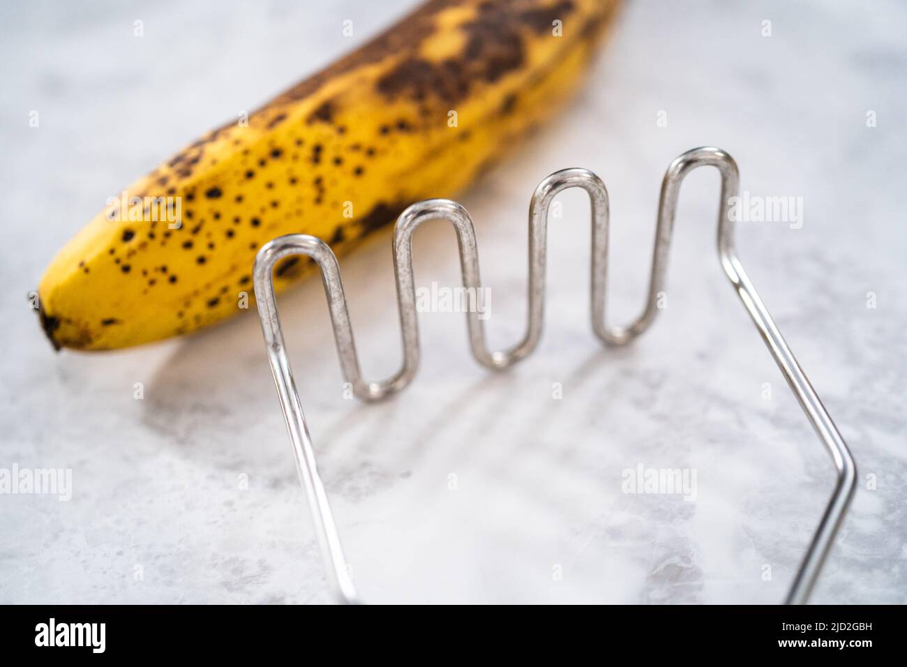 Mashing overhyped banana with a potato masher Stock Photo - Alamy