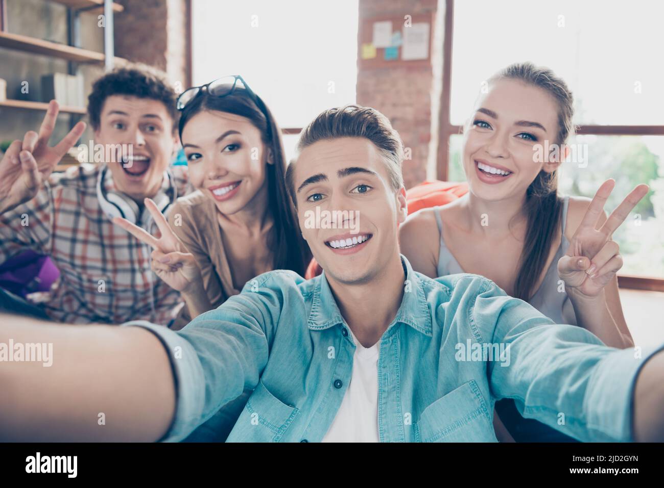 Photo of charming cute groupmates sitting dormitory beanbags showing v ...