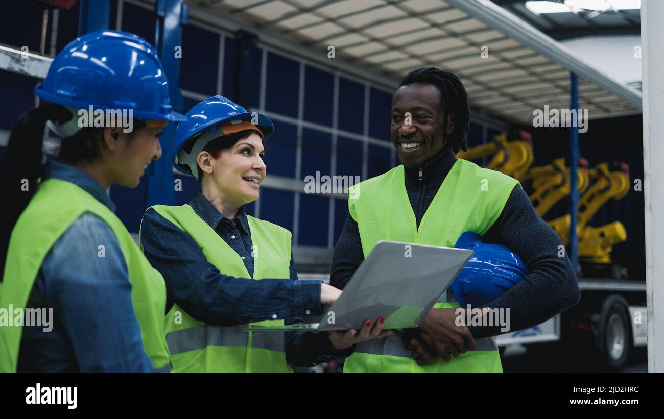 Team of multiracial engineers working in robotic factory monitoring the ...