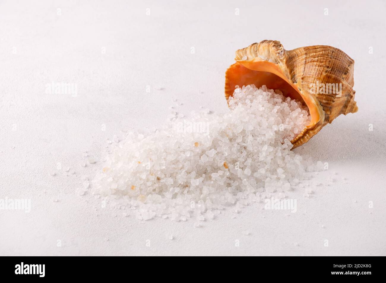 Organic spa sea salt is poured into a pile and a shell from the sea ...