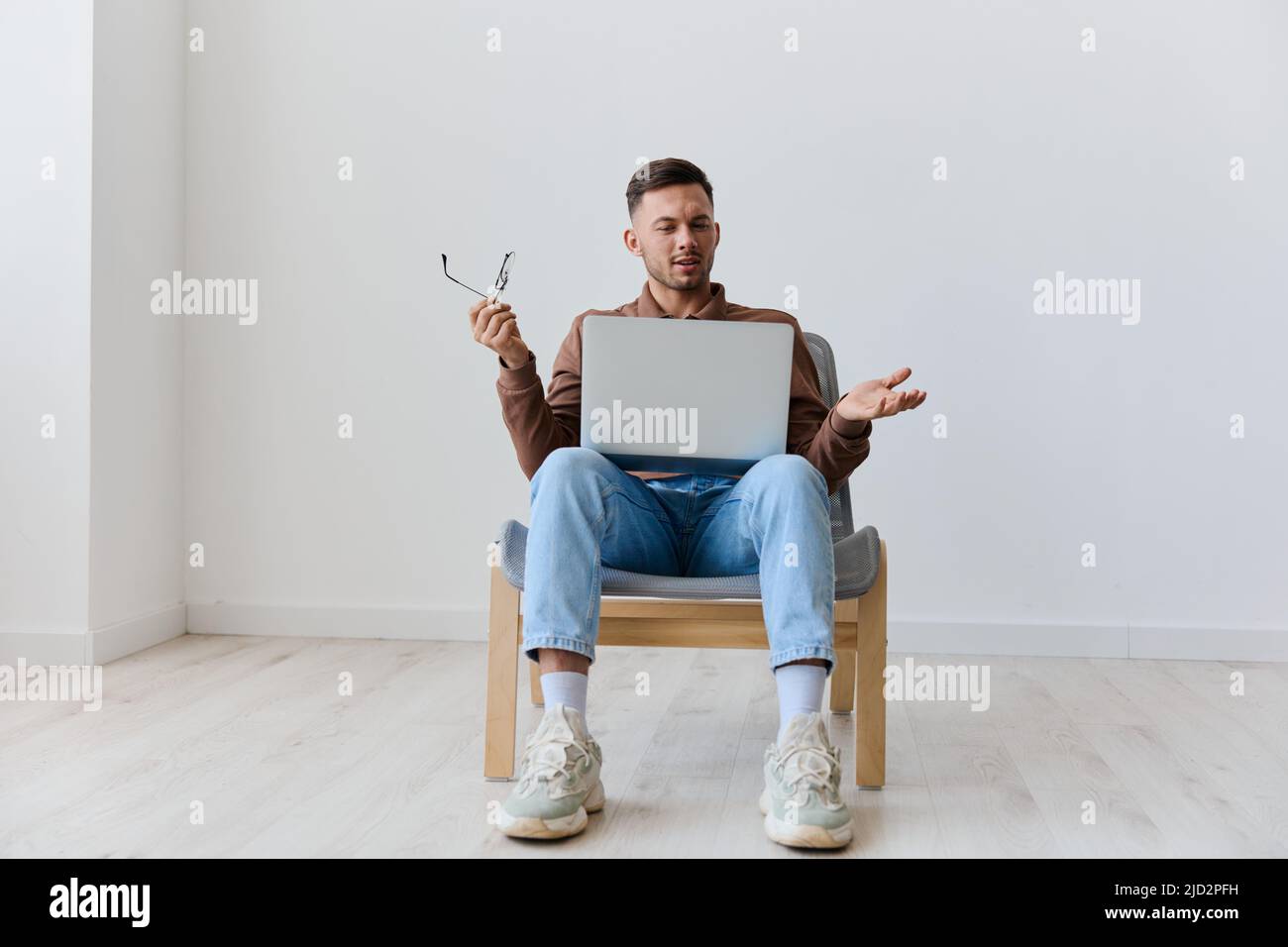 Confused shocked irritated young tanned man with laptop on knees can ...
