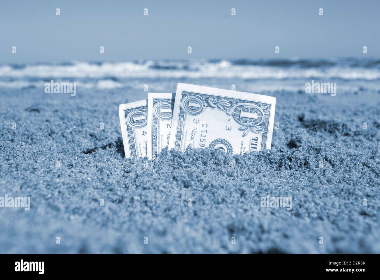 Paper bills one dollar buried in sand on beach backdrop of sea close-up ...