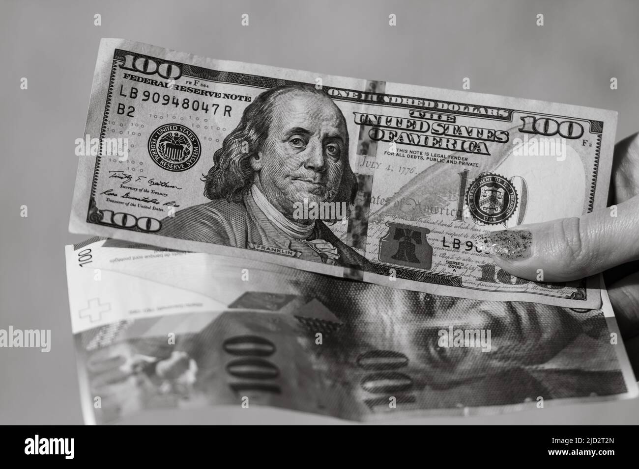 Hand holding money isolated on banknotes background. USD and CHF ...