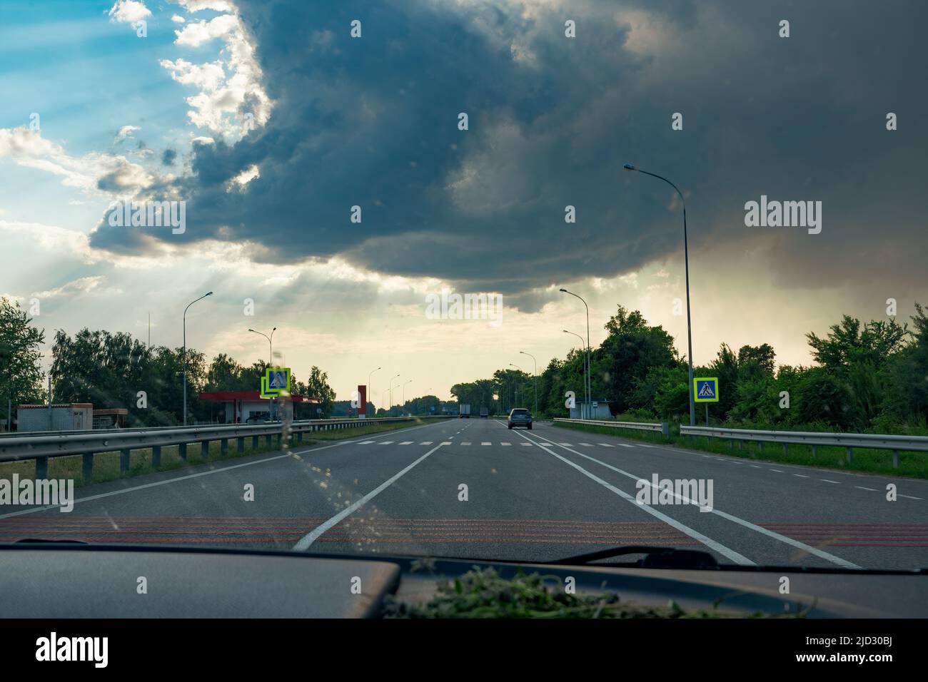 Driving on a highway with dramatic clouds and sun rays. Highway near ...