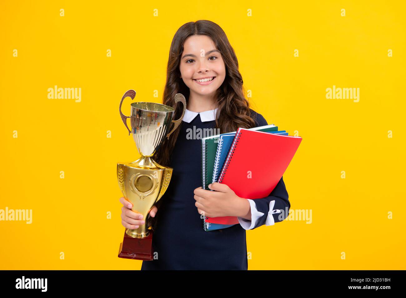Schoolgirl in school uniform celebrating victory with trophy. Teen ...