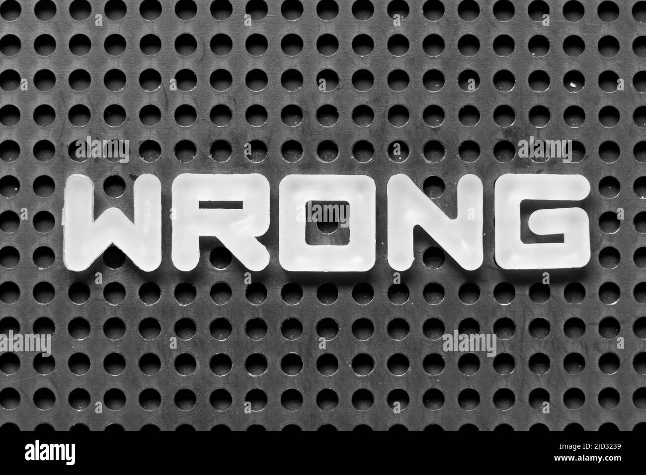 White alphabet letter in word wrong on black pegboard background Stock ...