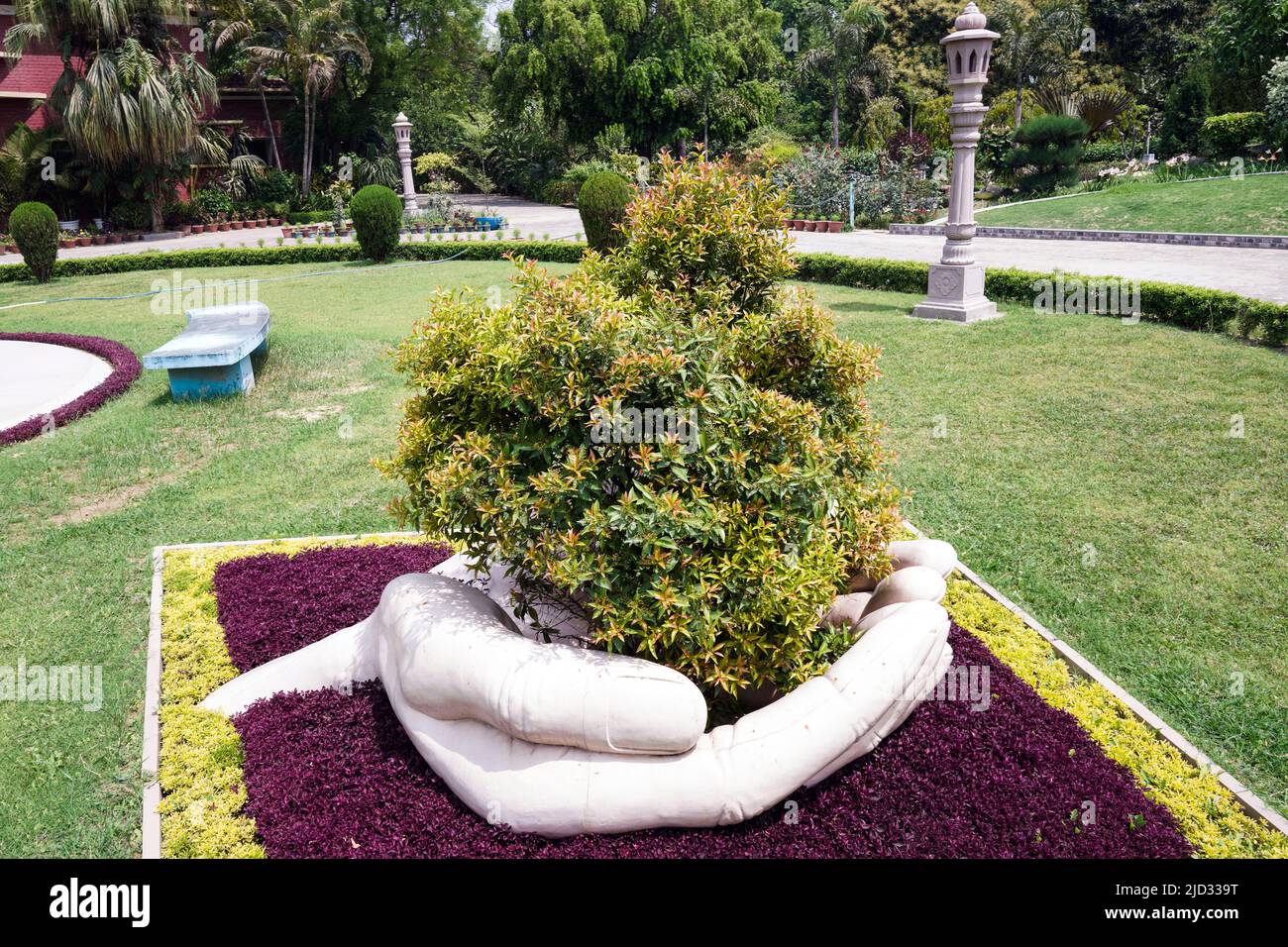 A large hand holds a bush in the Bishop's Garden of Varanasi, India ...