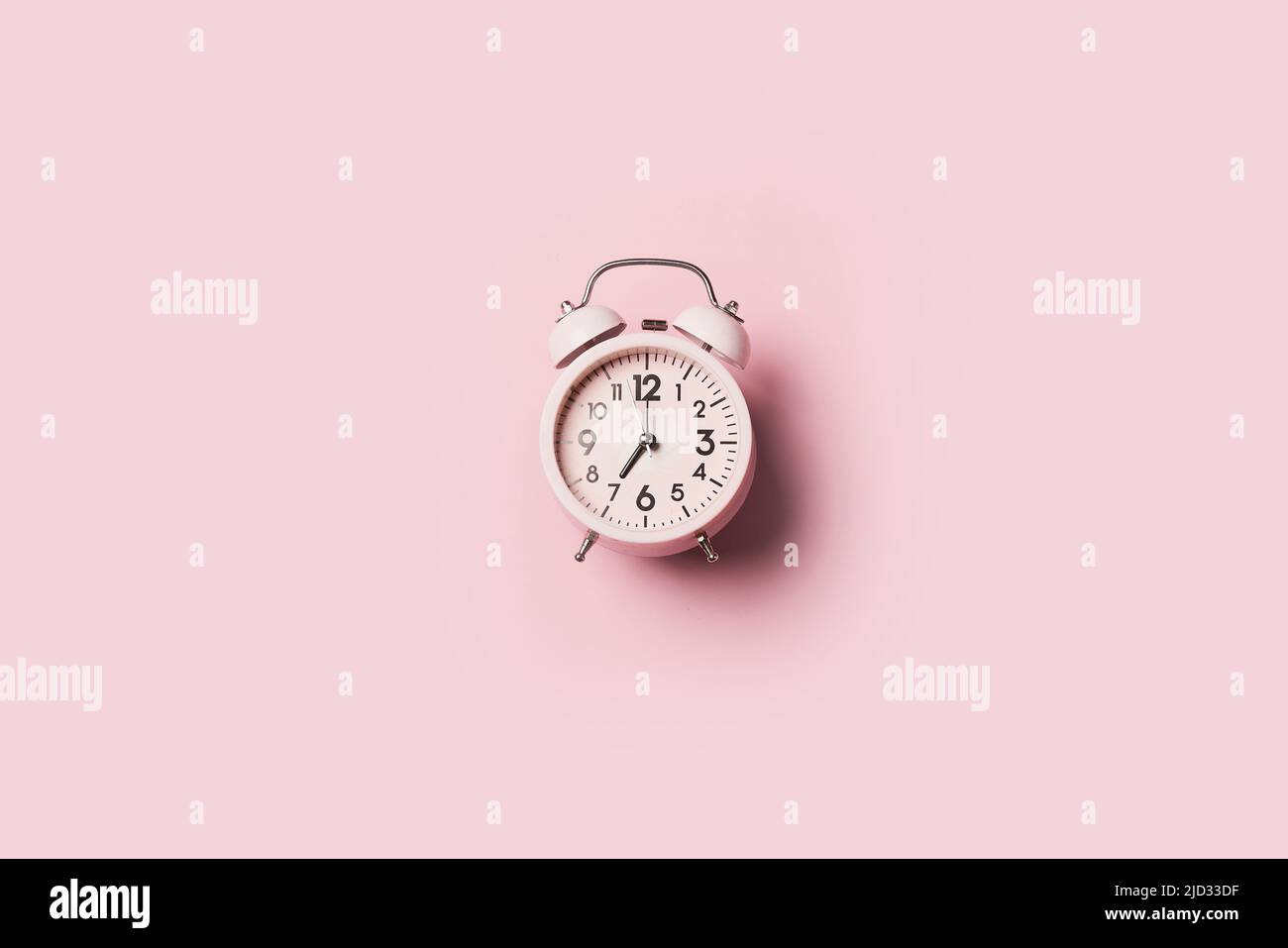 Pink alarm clock with hard shadow on pink background. Top view. Wake up ...