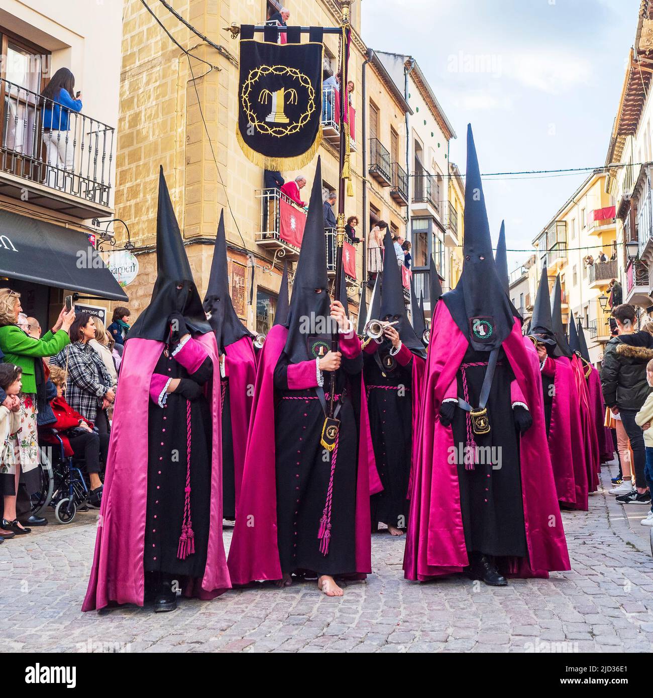 Cofrades in their traditional costumes with capirote, parading through ...