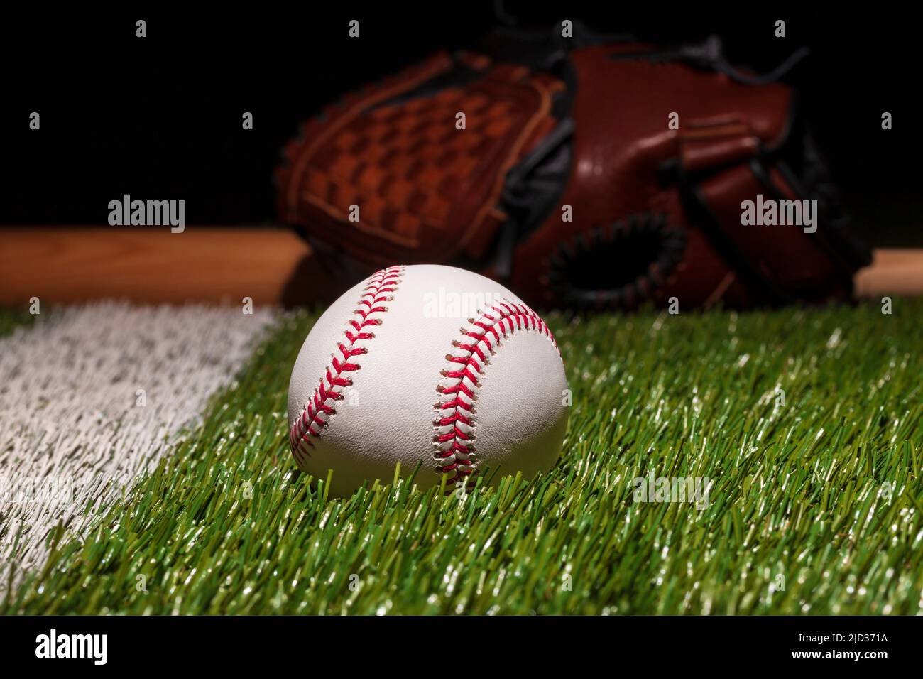 Baseball on grass field low angle close up with mitt and bat soft focus ...