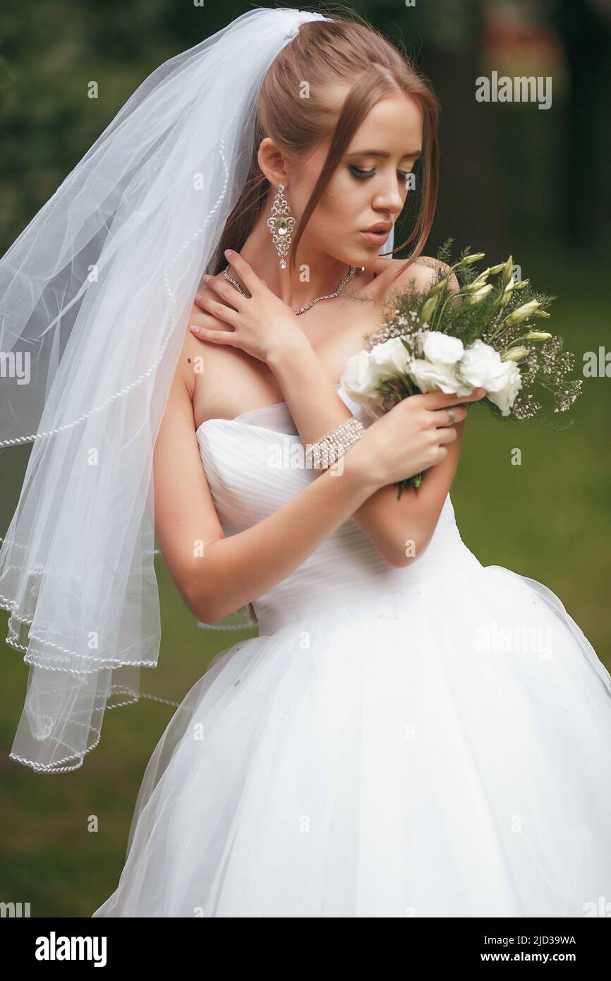 Beautiful bride in a magnificent wedding dress posing among greenery on ...