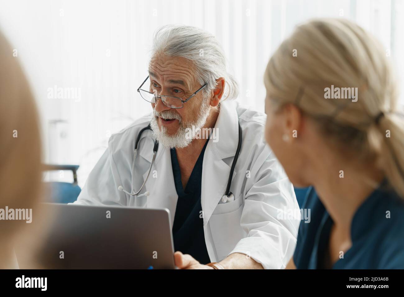 Group of doctors sitting at meeting table in conference room during ...