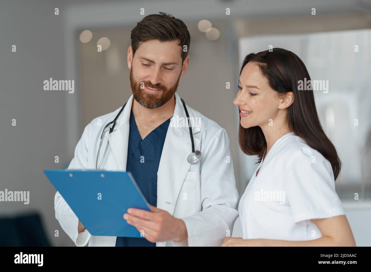 Two doctor colleagues discussing patient diagnosis stand in clinic hall ...