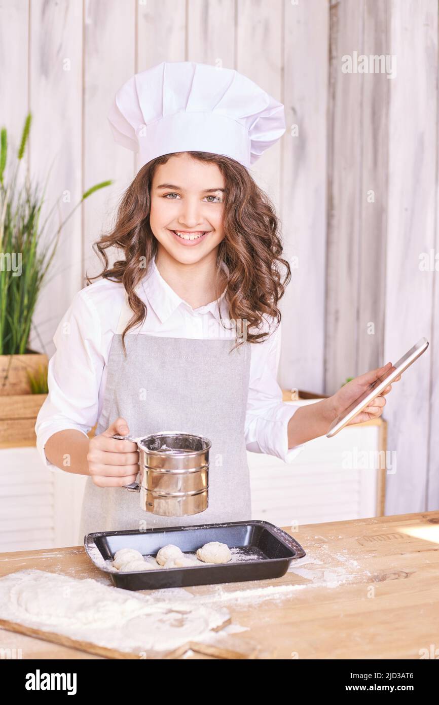 Young girl cooking at kitchen. Curly pretty child portrait. Chef ...