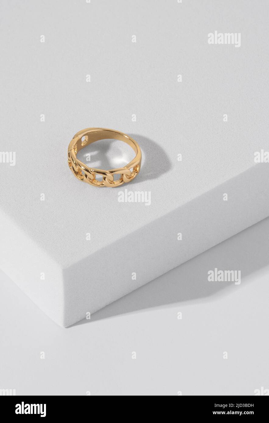 Top view of chain shape golden ring on white podium with copy space ...