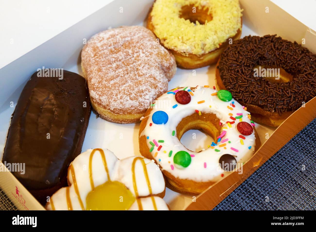 Box of sweets filled with colorful donuts and eclairs Stock Photo - Alamy