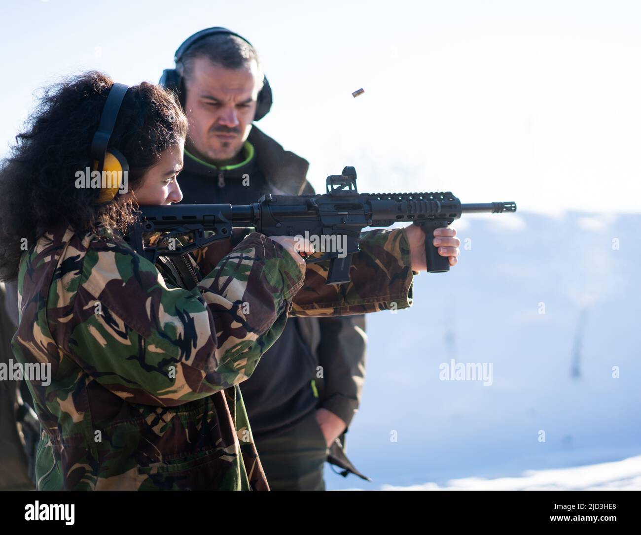 Trainer helping young woman to aim with handgun at combat training ...