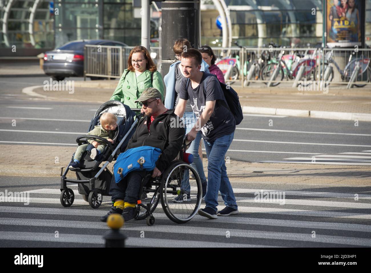 A man is seen pushing another man in a wheelchair and a woman pushing a ...