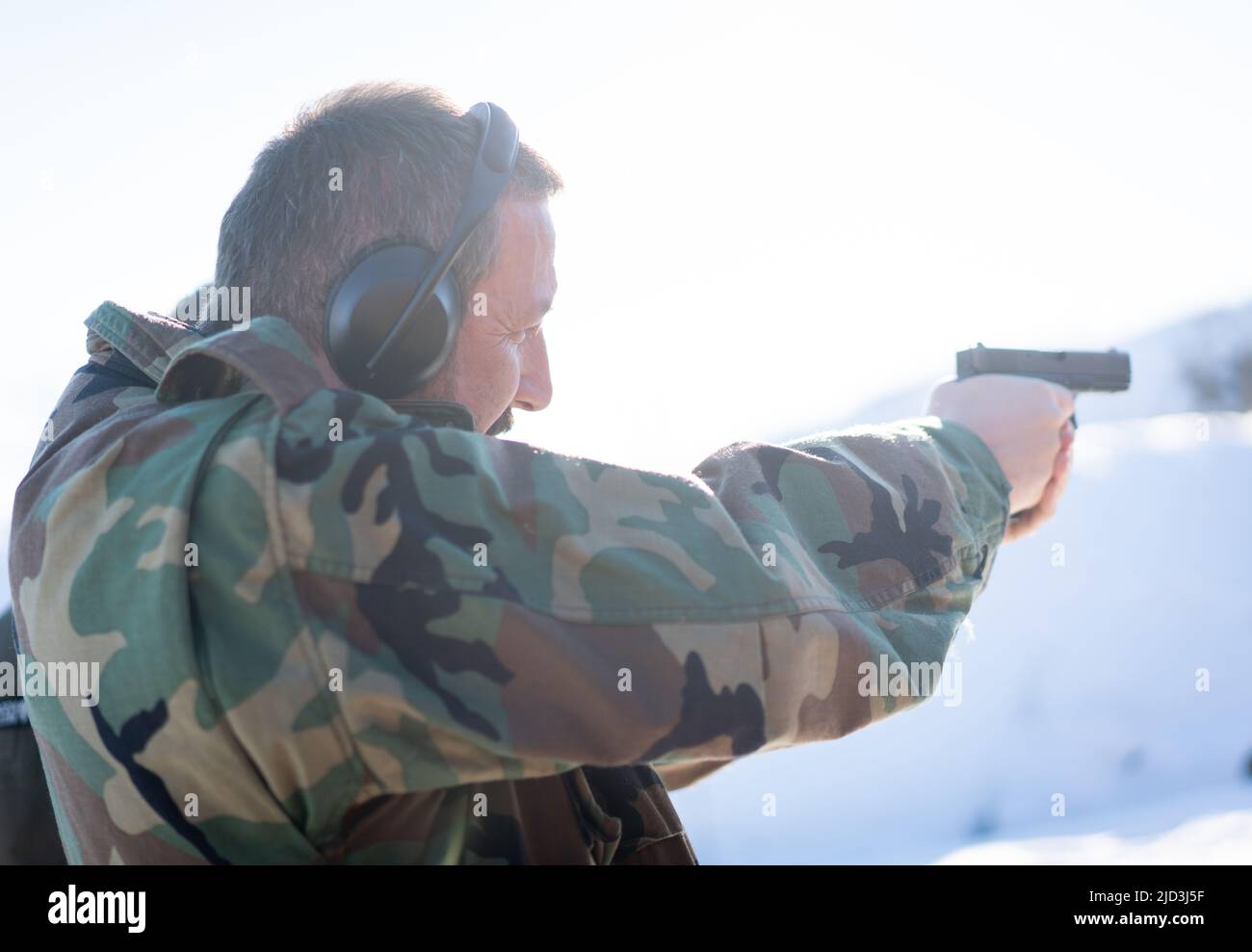 Trainer helping young person to aim with handgun at combat training ...
