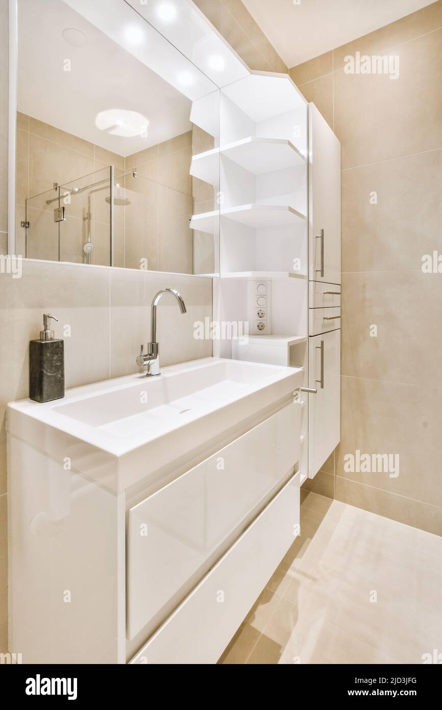 Sink with tap and liquid soap hanging on tiled wall under mirror in ...