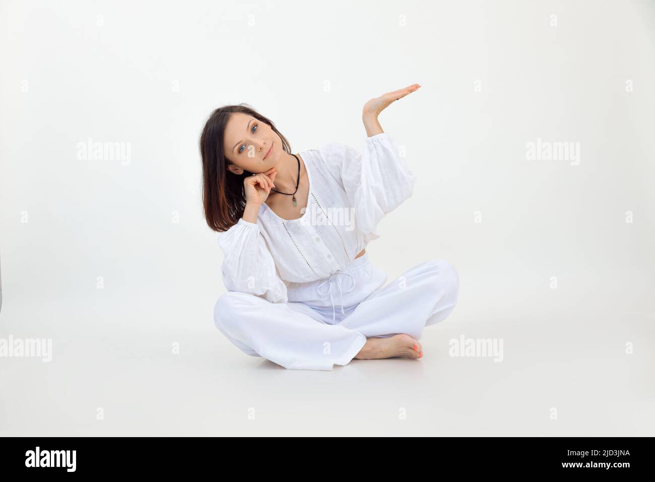Attractive relaxing brown-haired woman leaning on hand in lotus pose in ...