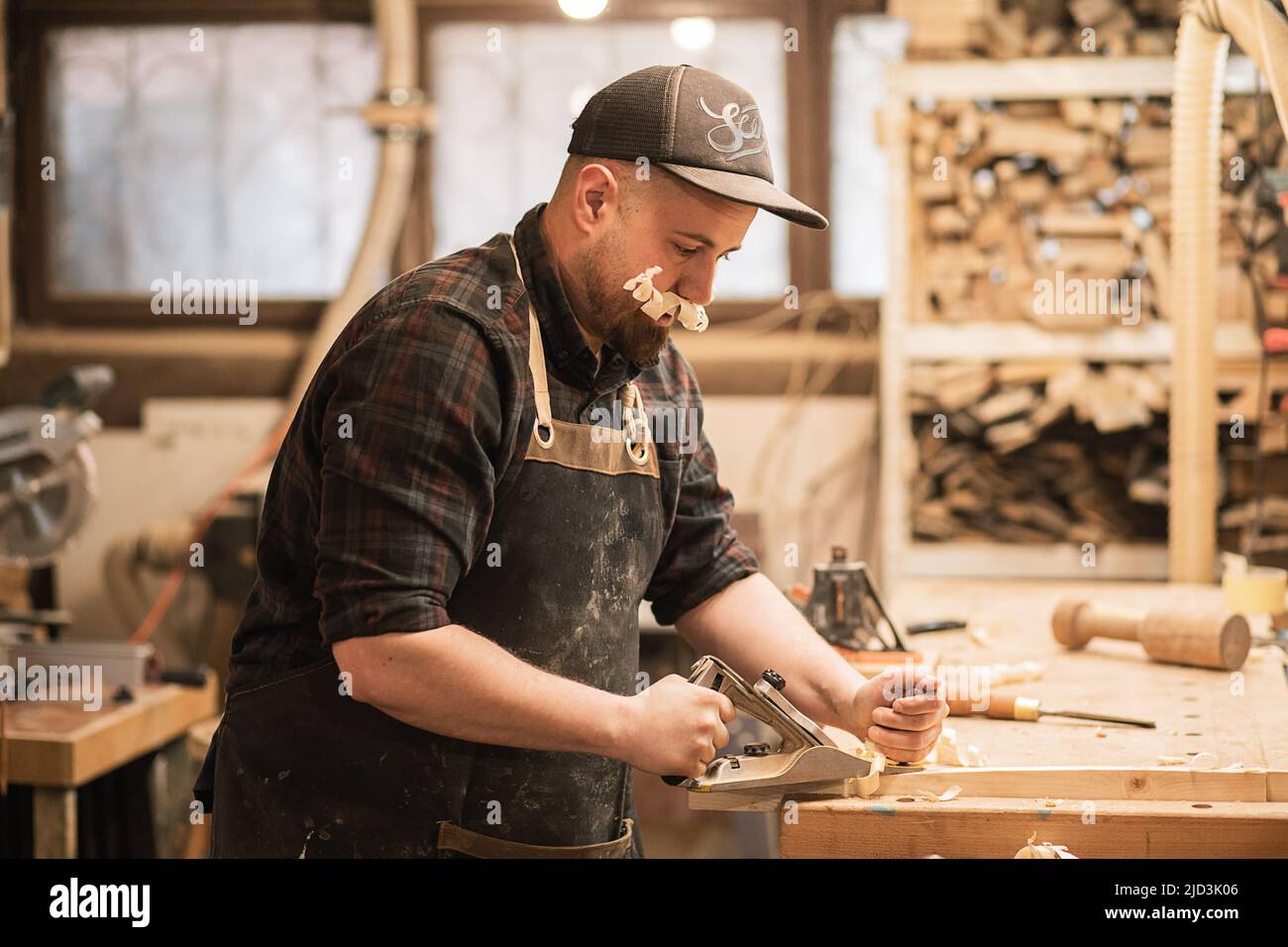 Concentrated, playful man, carpenter in cap and protective apron with ...