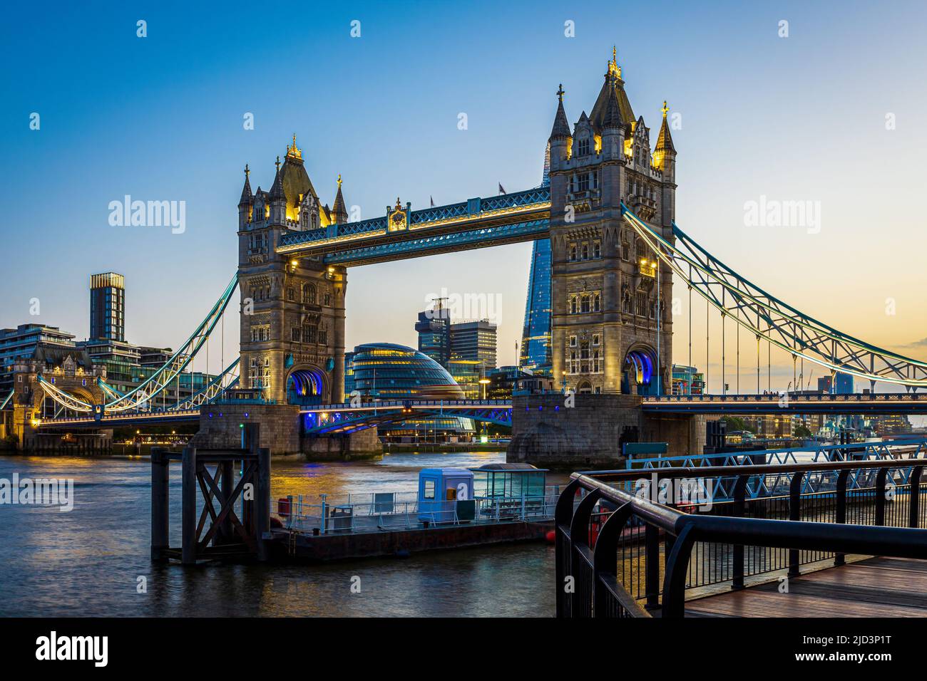 The illuminated Tower Bridge over the river Thames seen from the quay ...