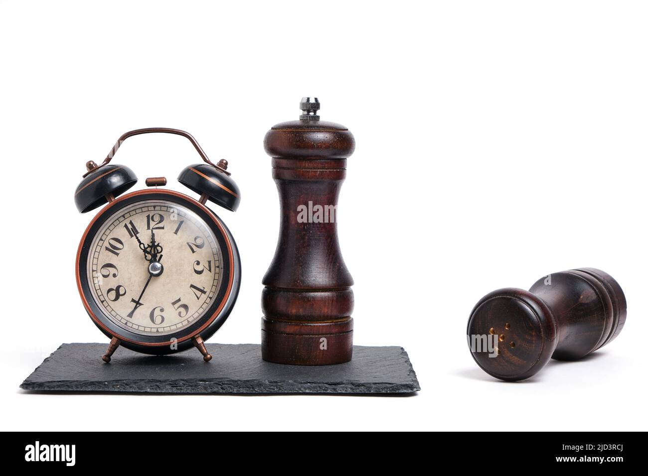 Alarm clock, wooden pepper shaker and salt shaker on a slate stone on a ...