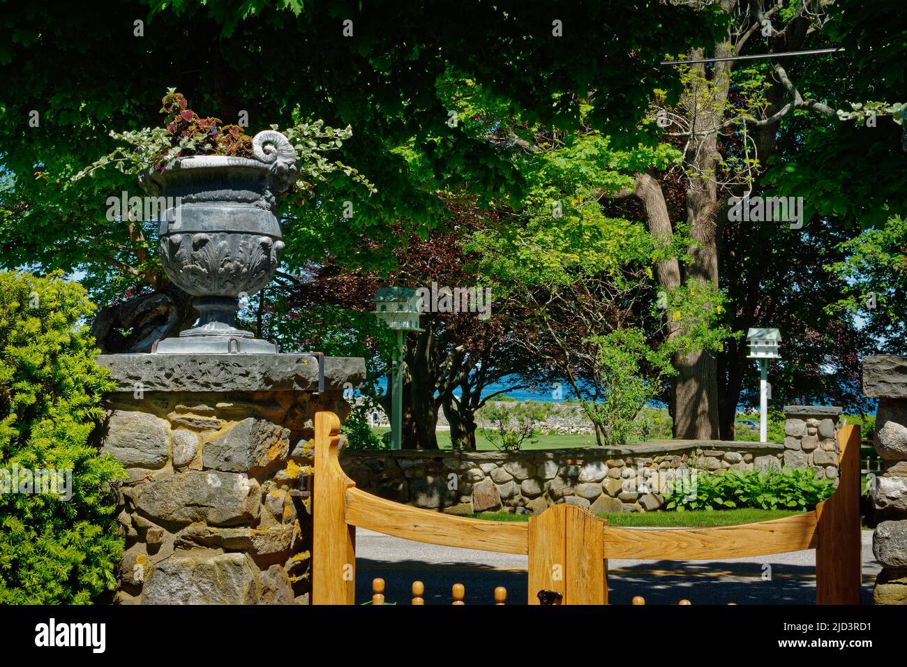 An ornate stone and wood gate with flower pot resting on columns and ...