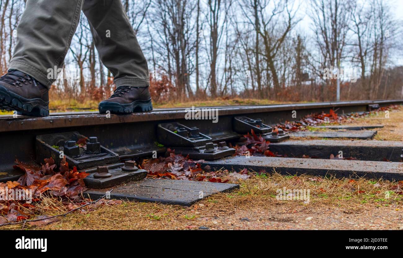 a human walks on the railroad, side view, legs in trousers and brown ...