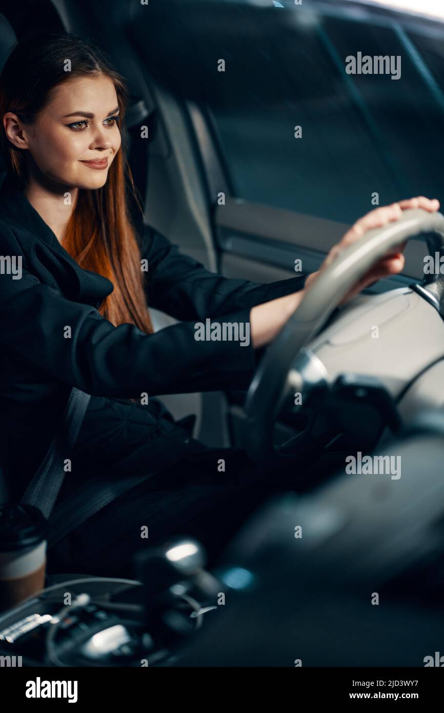 vertical photo of a pleasant, relaxed woman sitting behind the wheel of ...