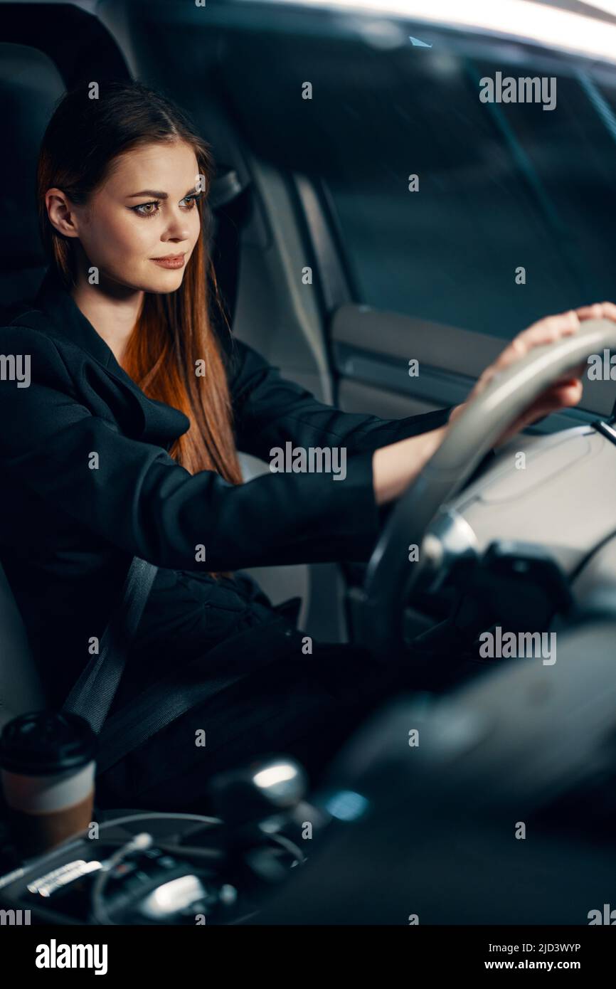 vertical photo of a pleasant, relaxed woman sitting behind the wheel of ...