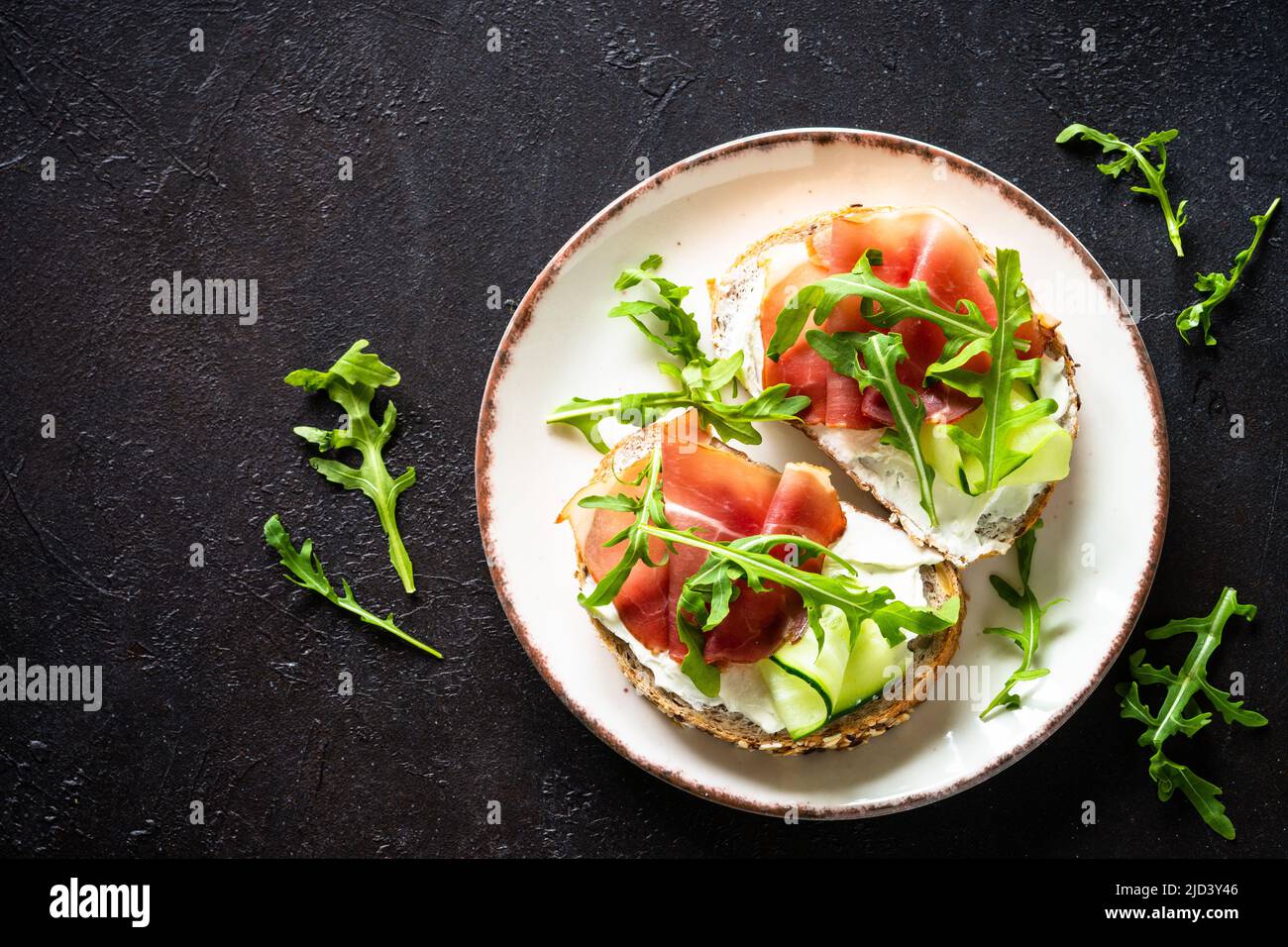 Open sandwich with cream cheese and prosciutto on dark Stock Photo - Alamy