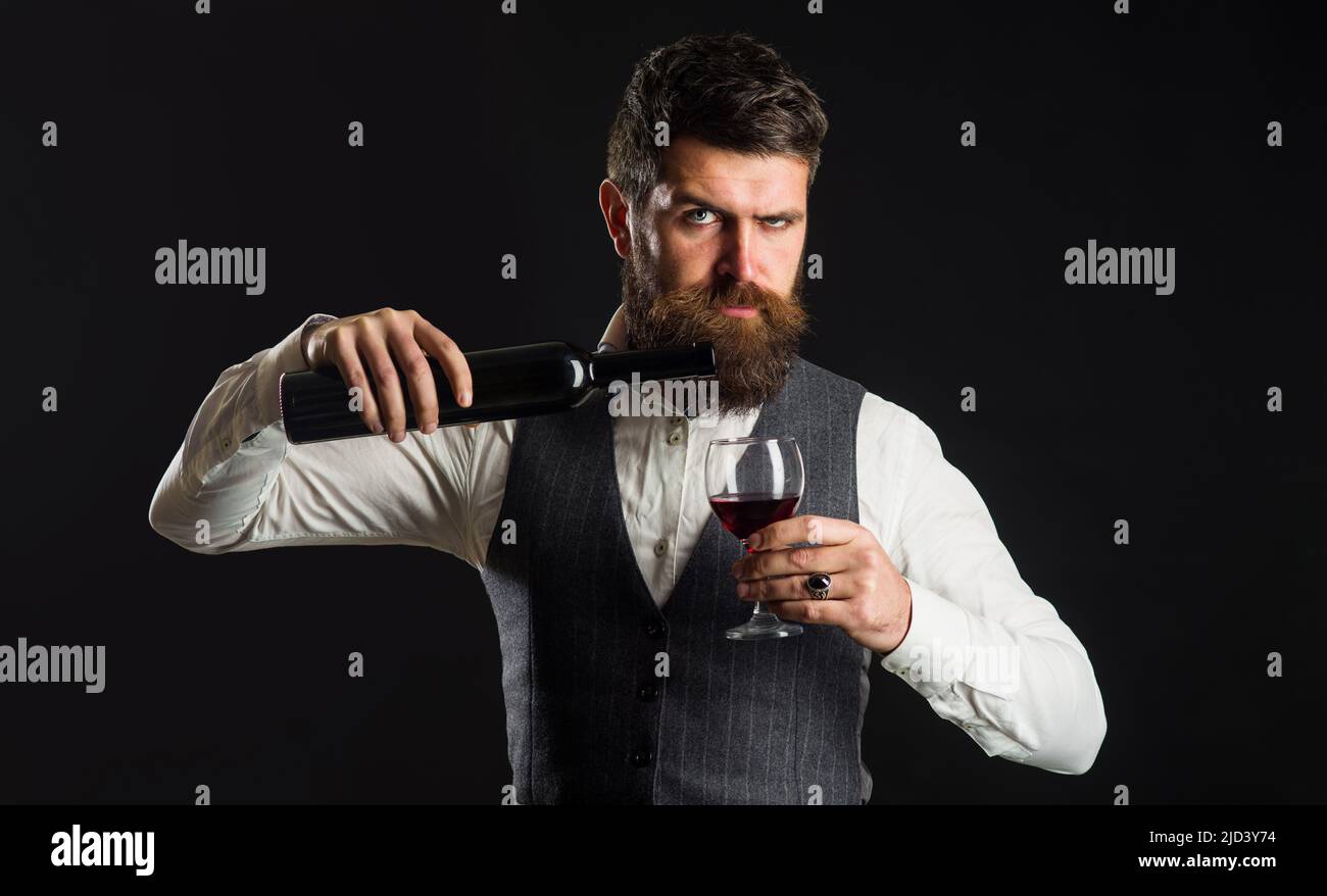 Bearded man pouring red wine with bottle in wineglass. Winery ...