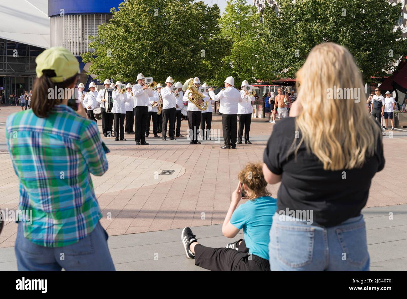 Crowd watch a band playing outside the O2 arena on a hottest summer day ...