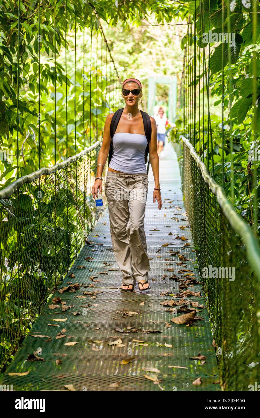 A woman tourist wearing light colors walks across a walking bridge in ...