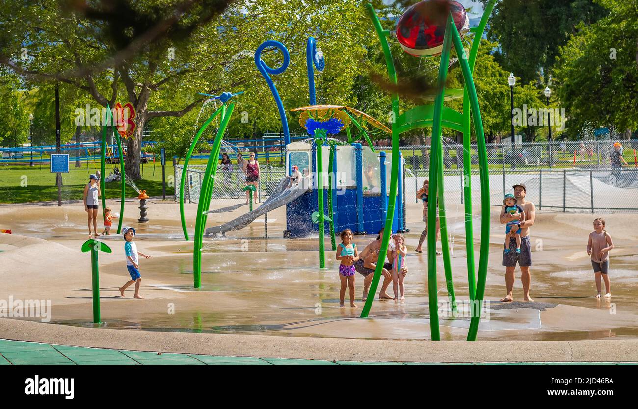 Diverse kids enjoy water splash pad or sprayground at Park Playground. Water fountain activities ...