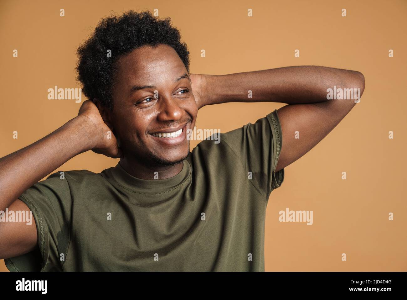 Young black man wearing t-shirt smiling while covering his ears ...