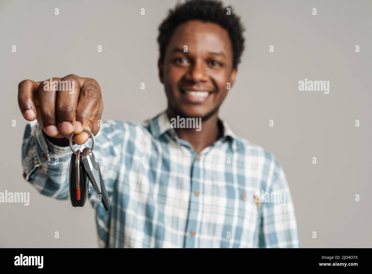 Young black man smiling while showing keys at camera isolated over ...