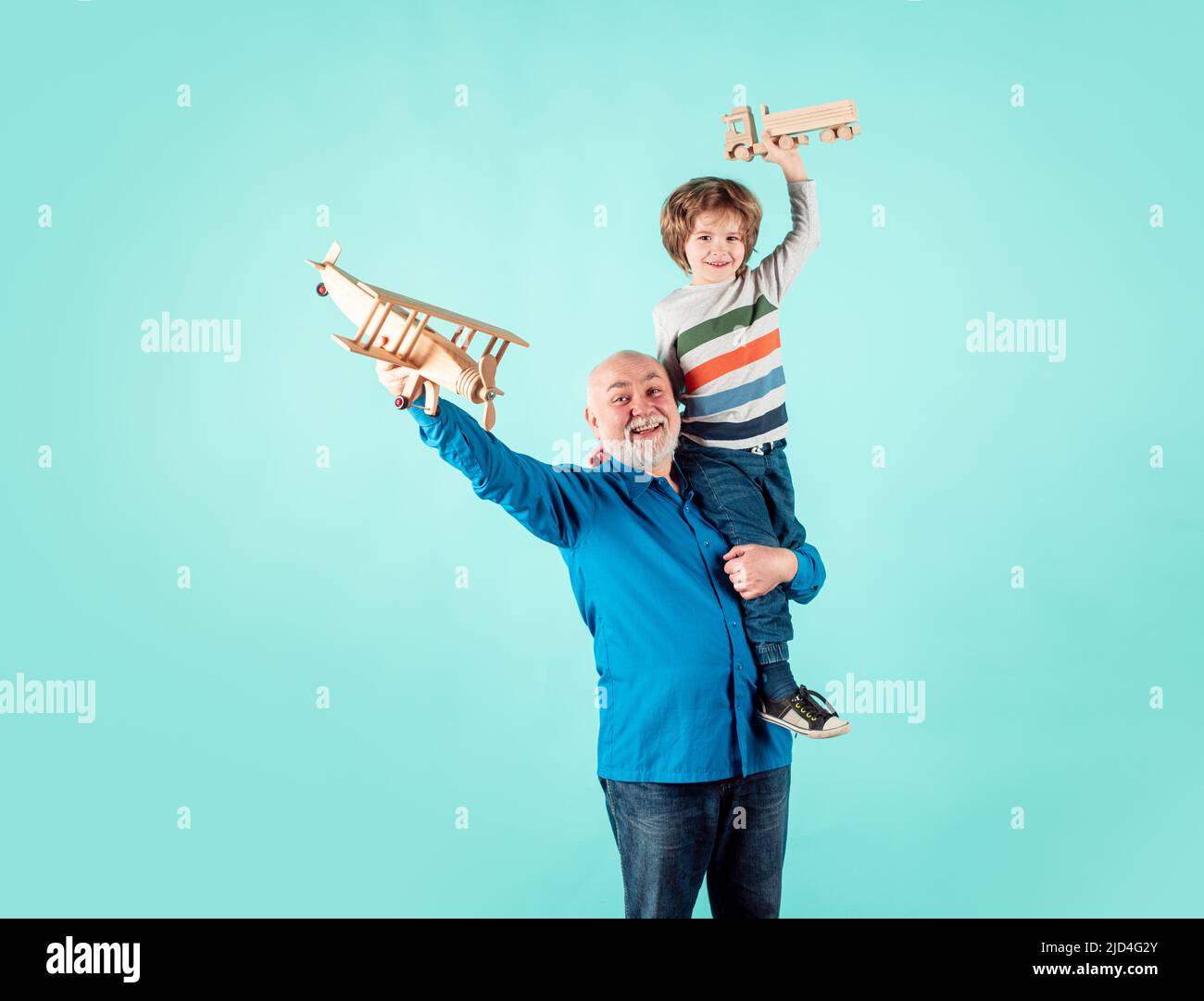 Child boy and grandfather piggyback with toy plane and wooden truck ...
